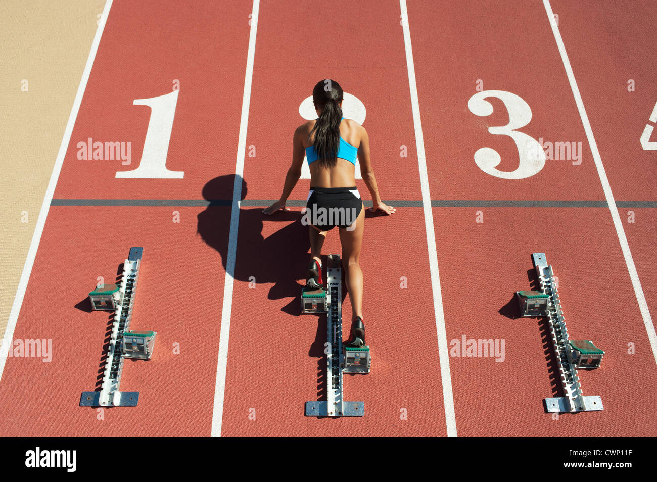Female athlete in starting position on running track, rear view Stock ...