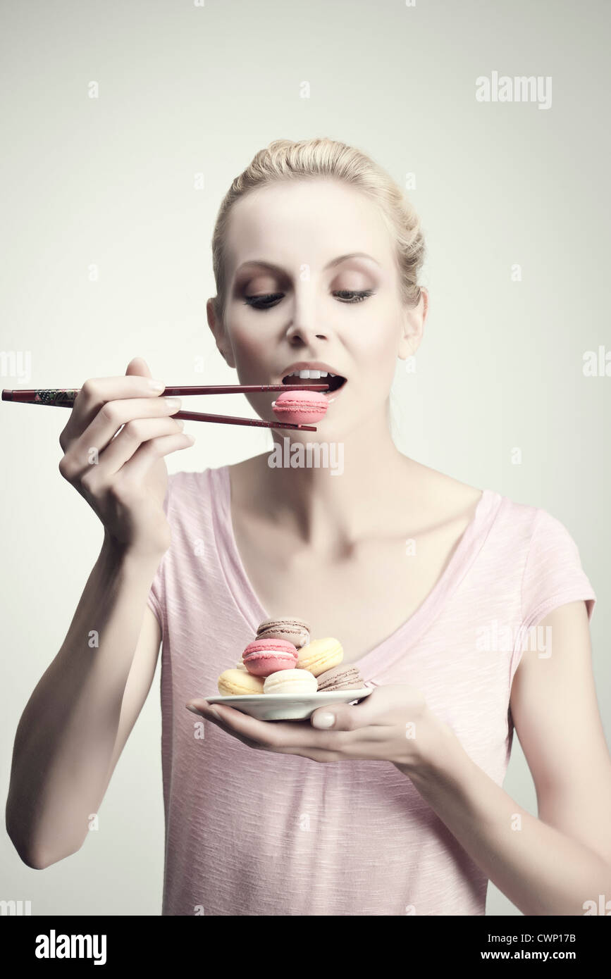 Young woman holding macaroon with chopsticks, portrait Stock Photo - Alamy