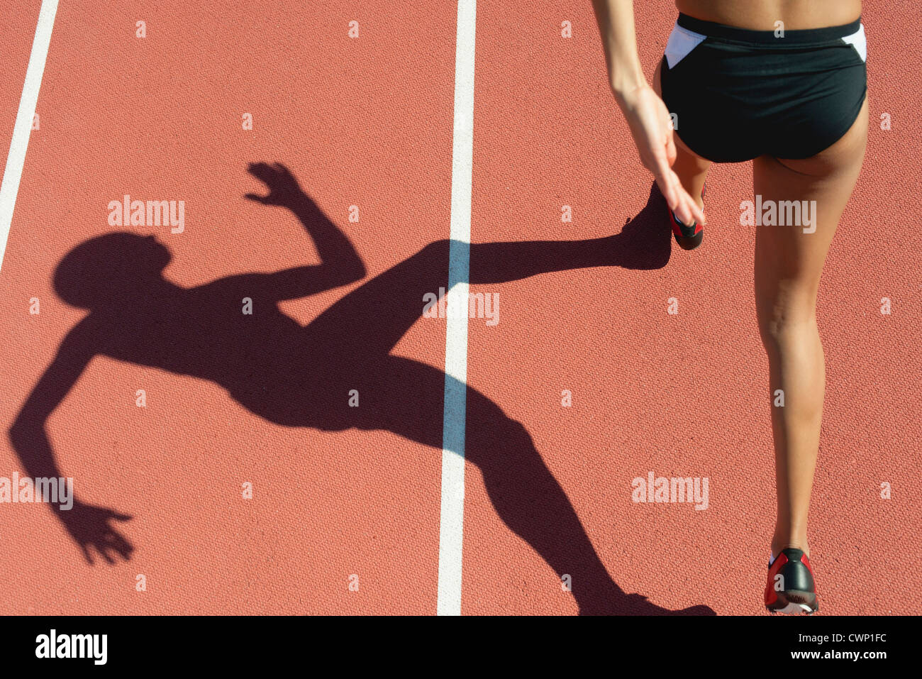 Female athlete running on track, low section, focus on shadow Stock ...
