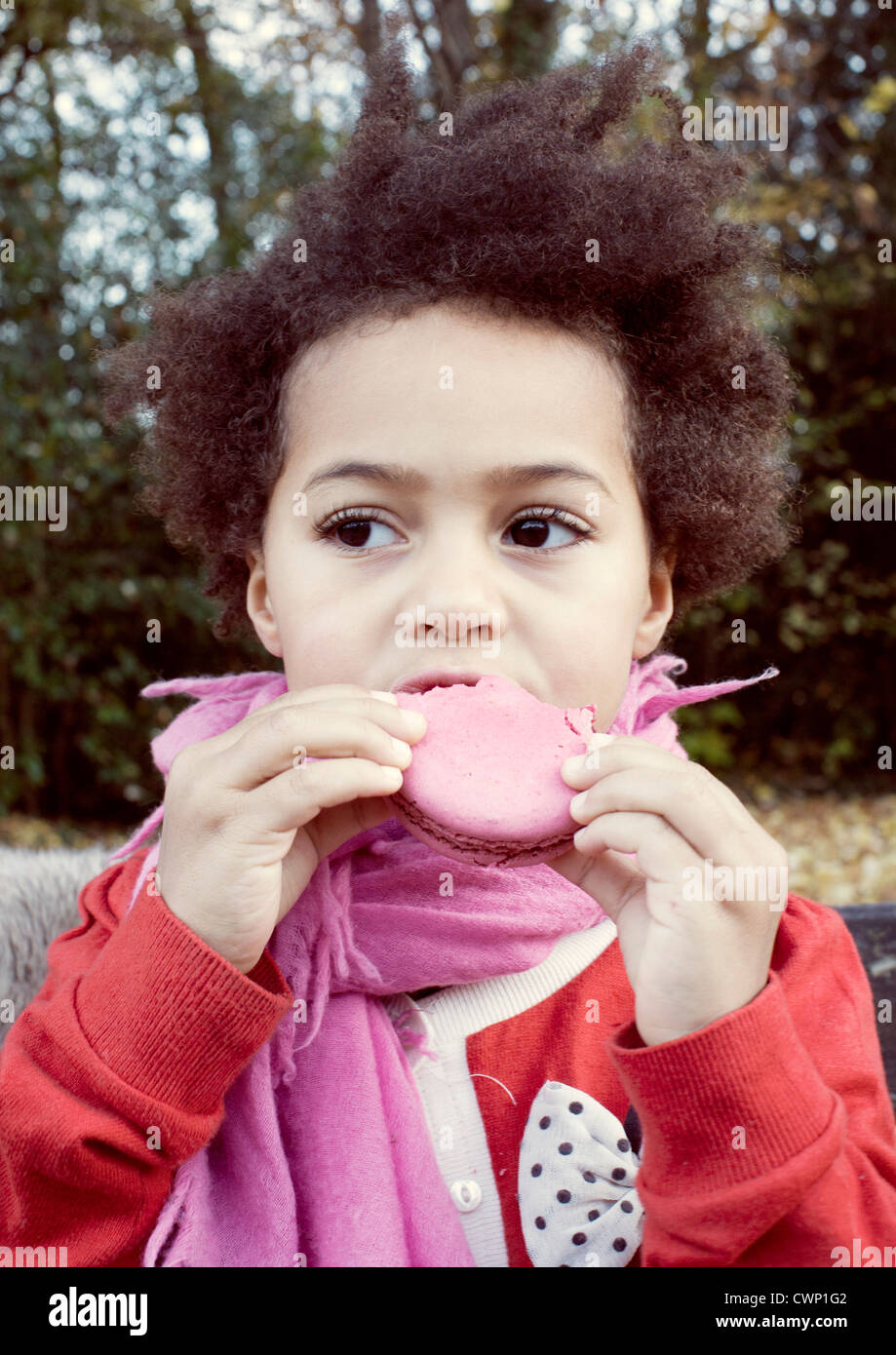 Little girl eating macaroon, portrait Stock Photo - Alamy