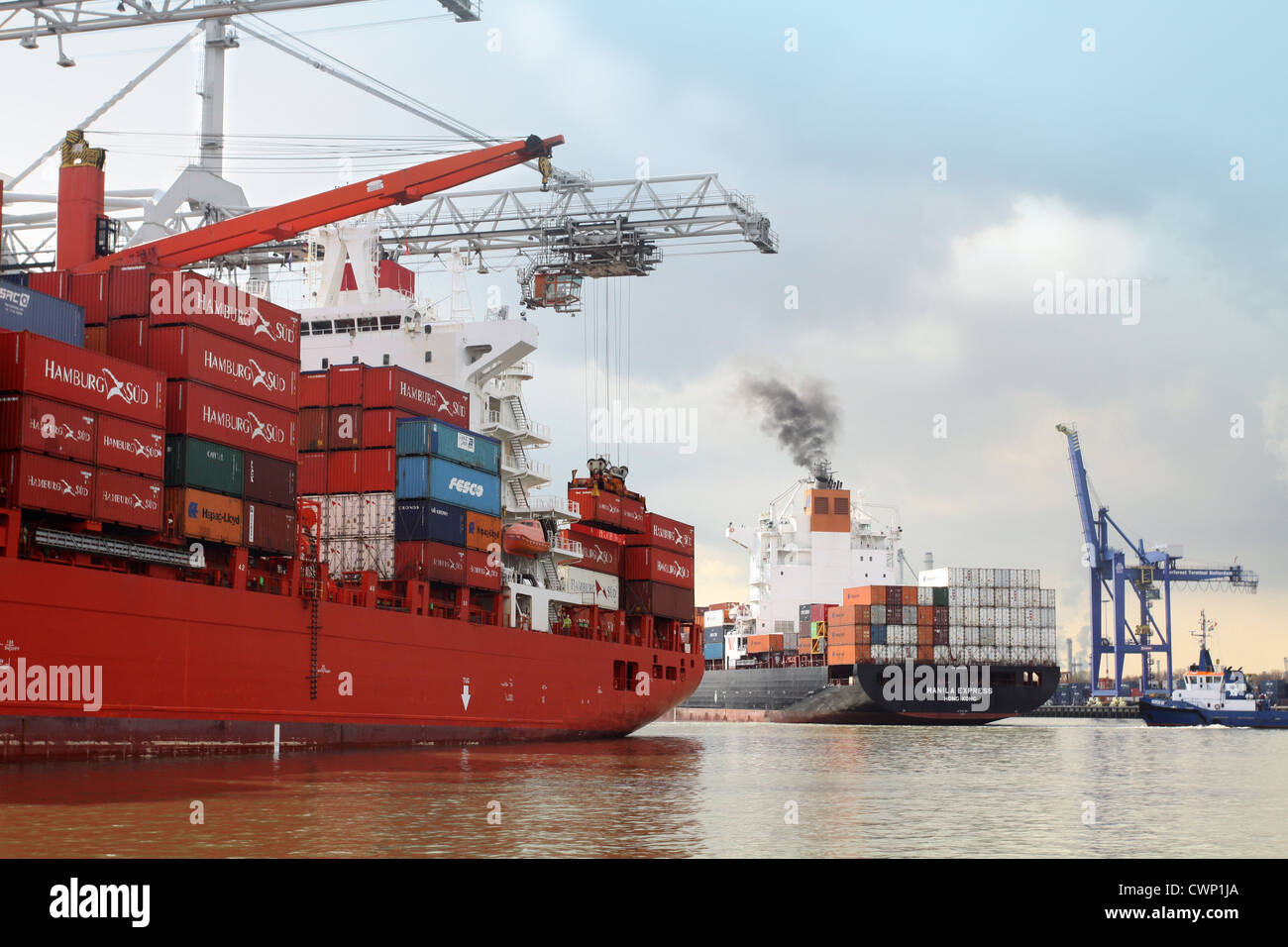 Busy port scene in Rotterdam; containerships, tug, smoke belching from ...