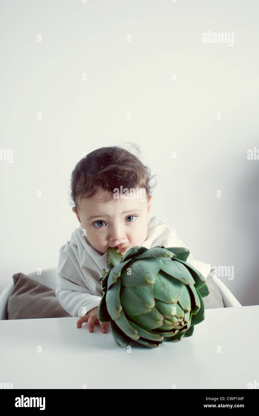 Infant biting into artichoke stem, portrait Stock Photo - Alamy