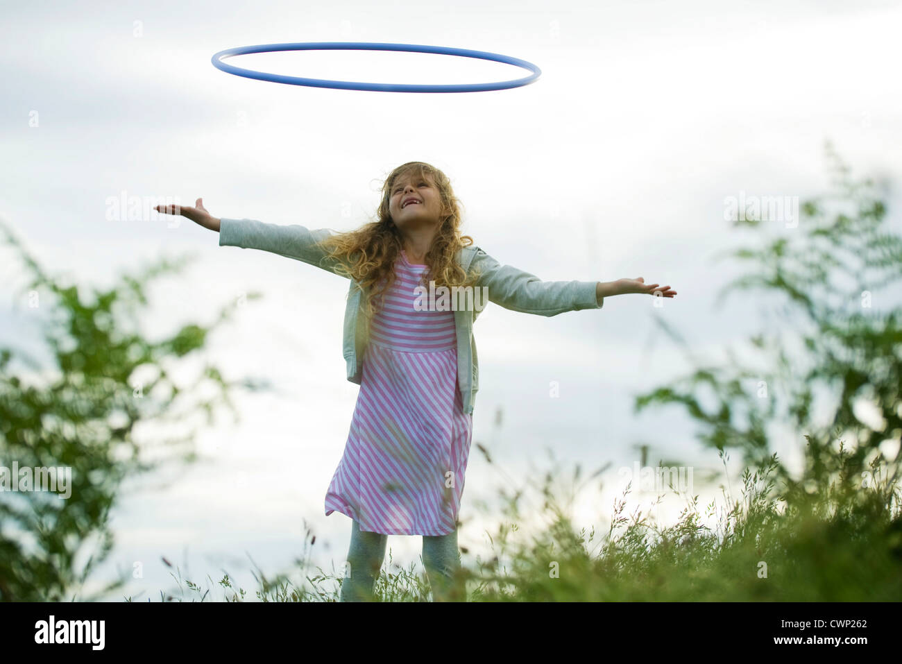 Girl throwing plastic hoop in air Stock Photo - Alamy