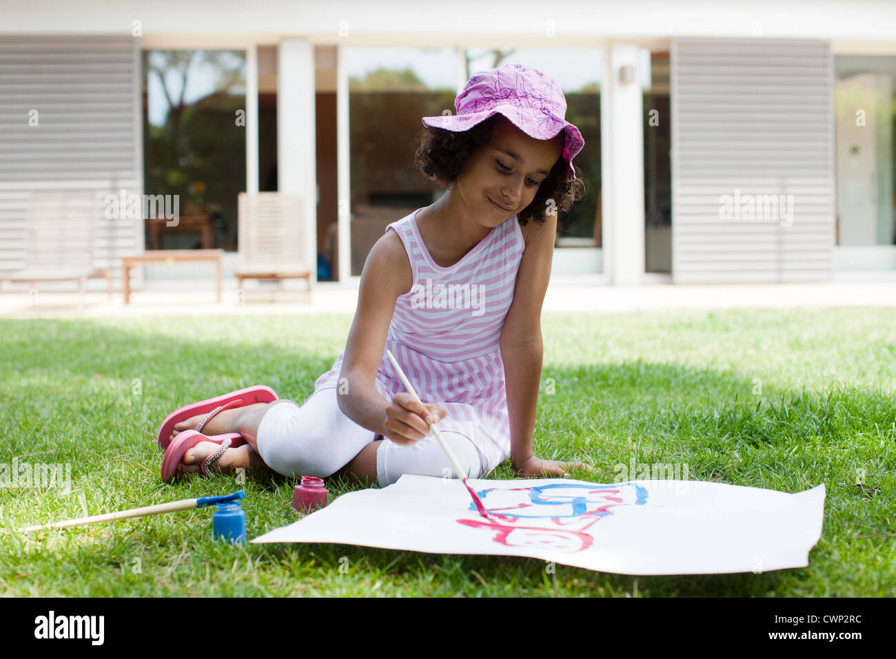 Girl sitting on grass drawing on paper Stock Photo - Alamy