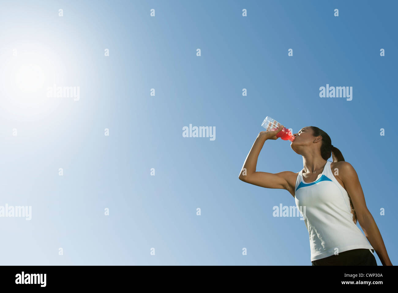 Female athlete drinking sports drink, low angle view Stock Photo - Alamy