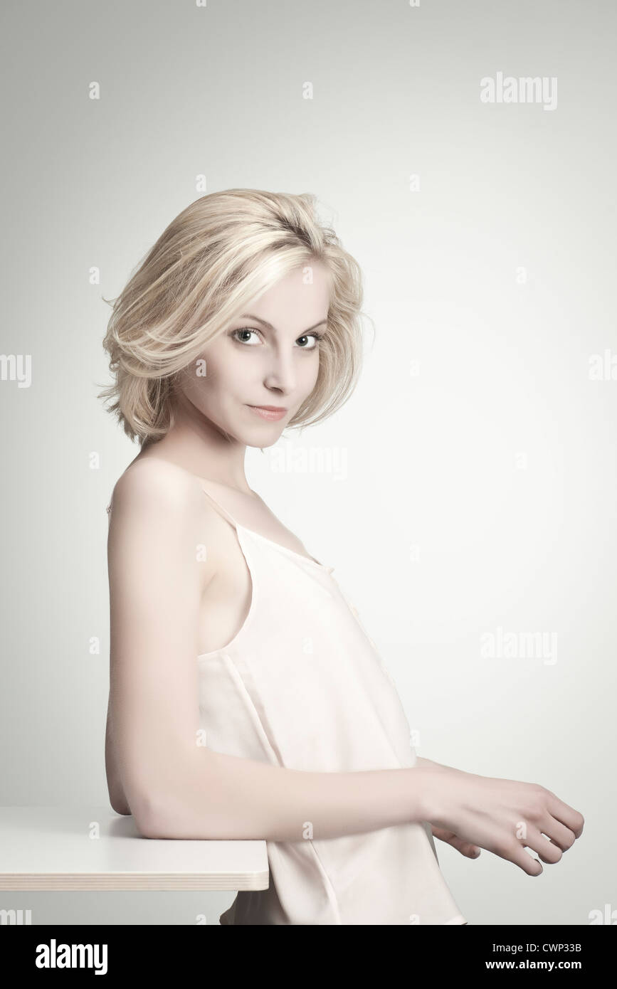 Young woman leaning against table, portrait Stock Photo - Alamy