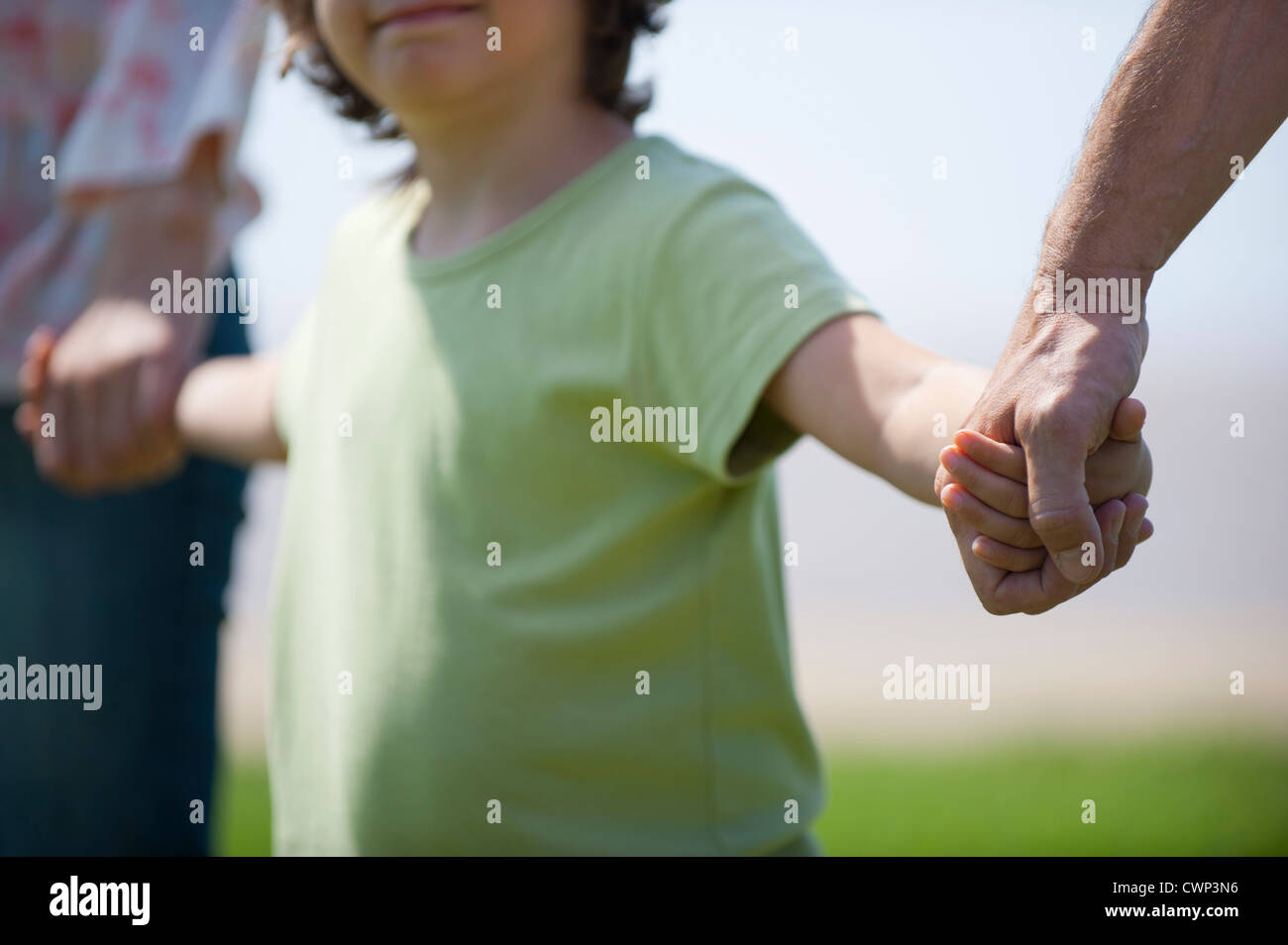 Boy holding hands with parents, cropped Stock Photo - Alamy