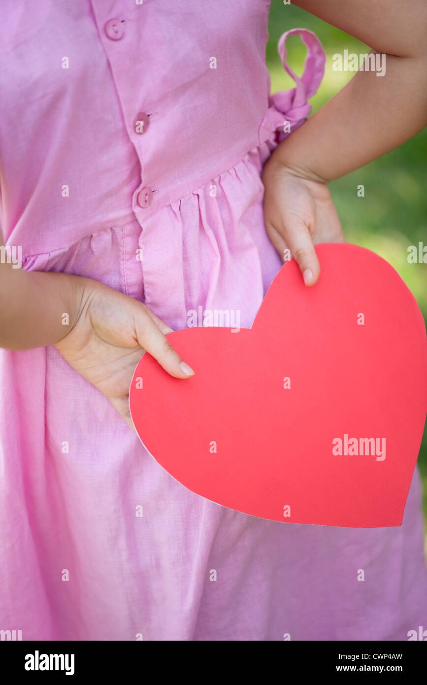 Girl holding paper heart behind back, cropped Stock Photo - Alamy