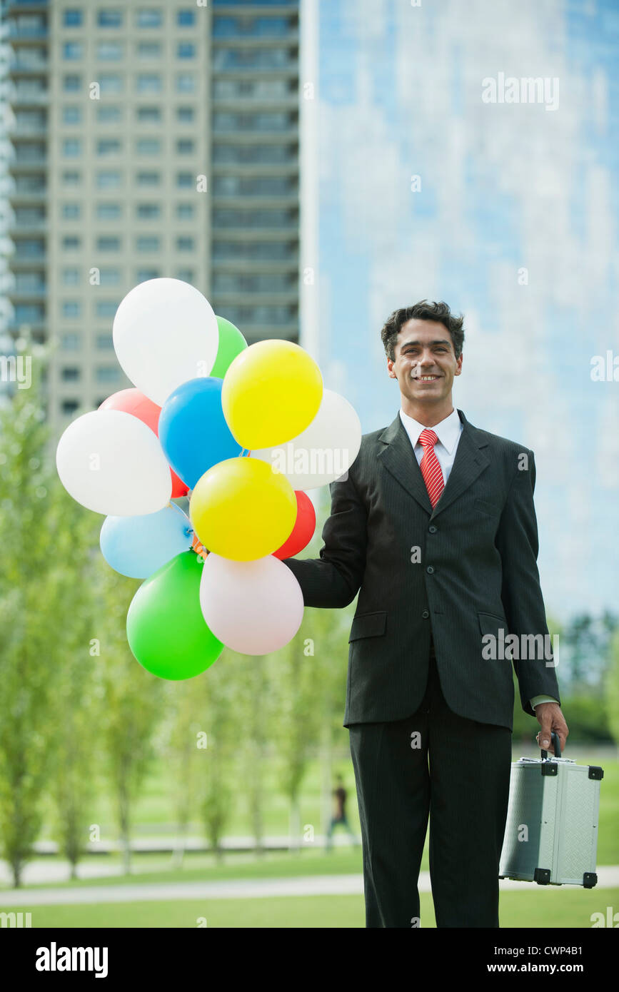 Smiling businessman holding bunch of balloons Stock Photo - Alamy
