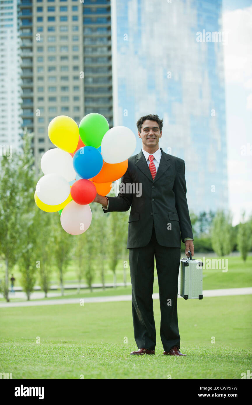 Smiling businessman holding bunch of balloons Stock Photo - Alamy
