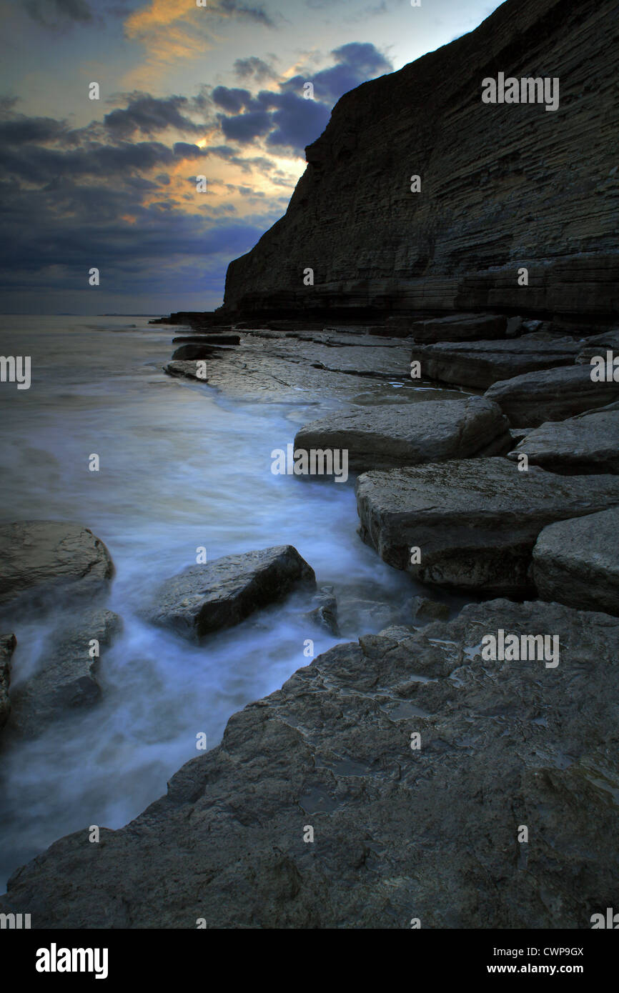 View of rock formations and cliffs in rugged bay at sunset, Dunraven ...