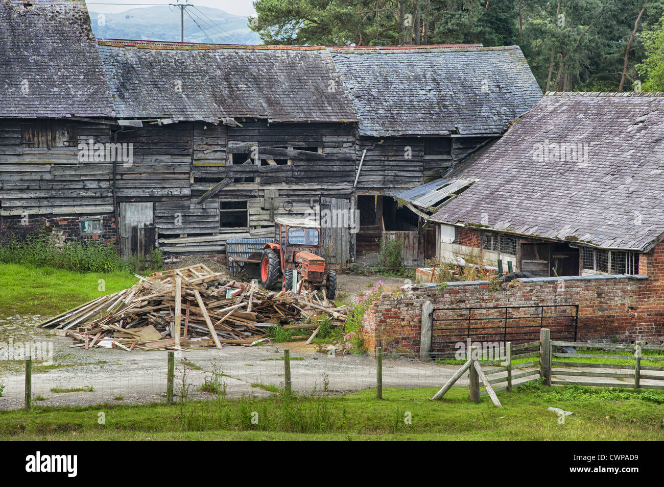 Derelict farmyard with old farm buildings and tractor, Newtown, Powys ...