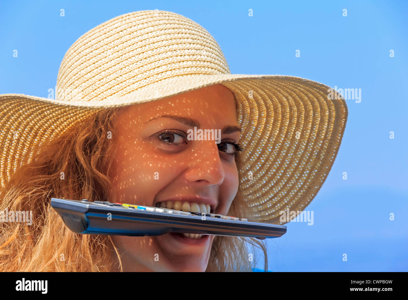 Beautiful girl biting a remote control Stock Photo - Alamy