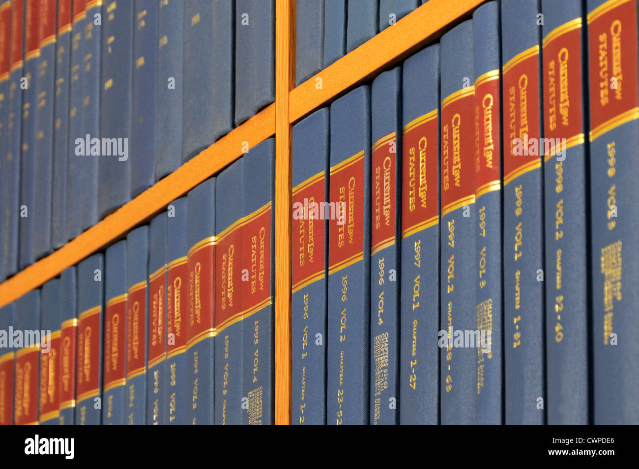 A bookcase displaying a line of identical blue, red and gold books ...