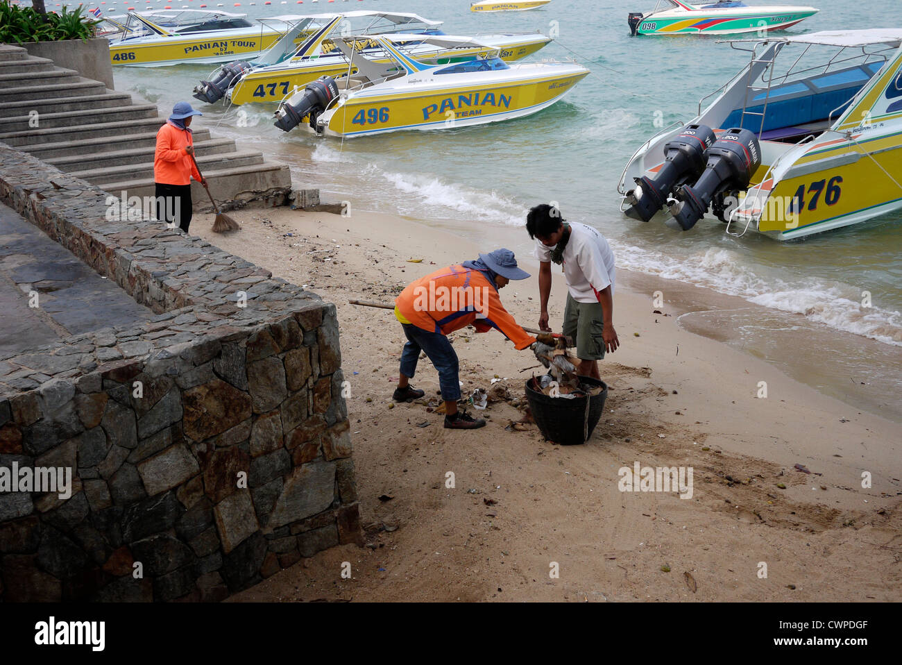 Beach cleaners sweep and clear rubbish from the beach in Pattaya ...