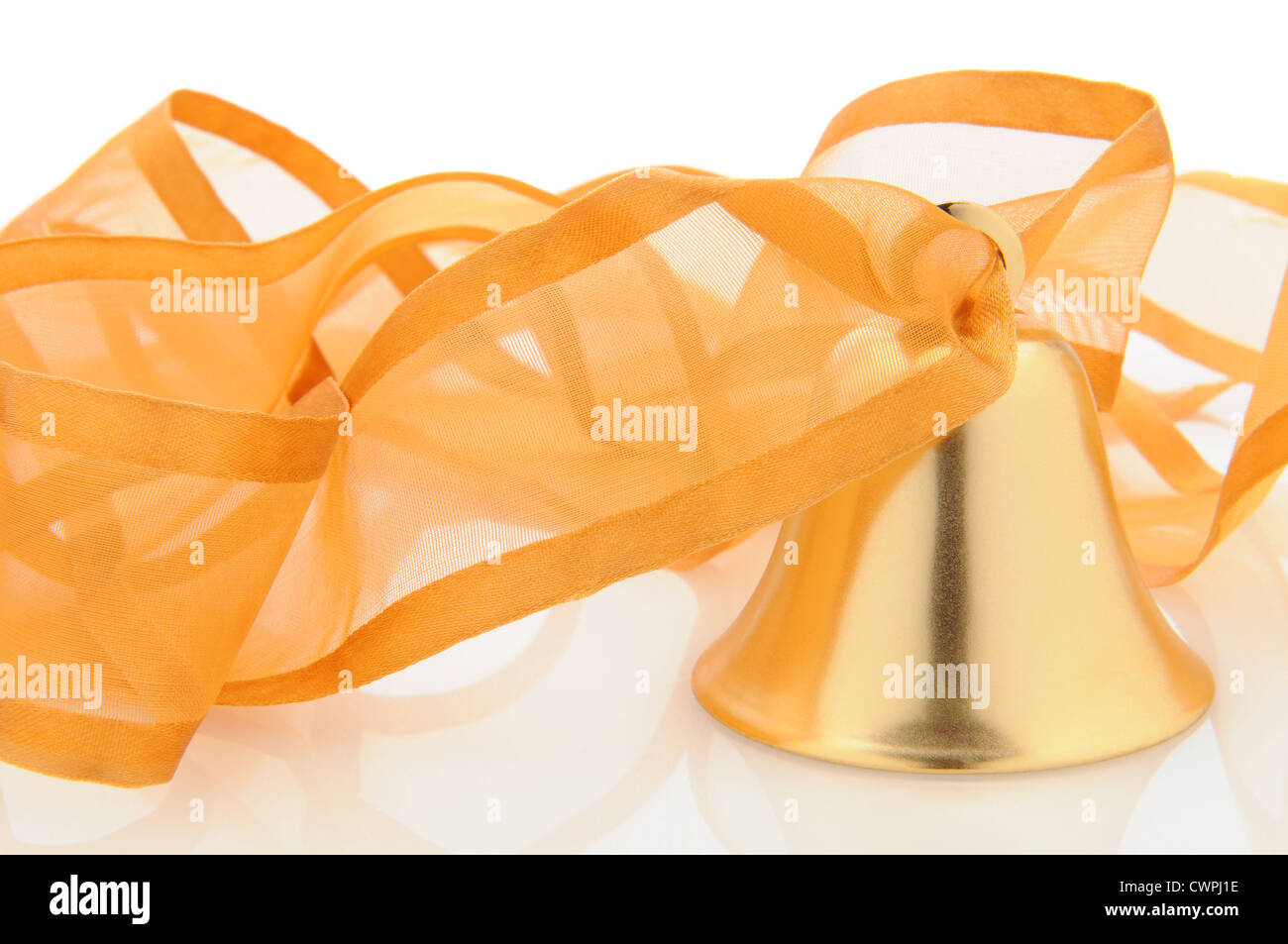 Closeup of a brass Christmas bell with gold ribbon over a white ...