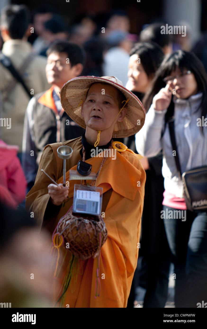 A Buddhist Nun stands in the middle of a busy street during a festival ...