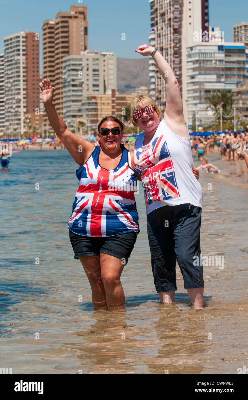 Two British women wearing Union Jack tee shirts in the sea at Benidorm ...