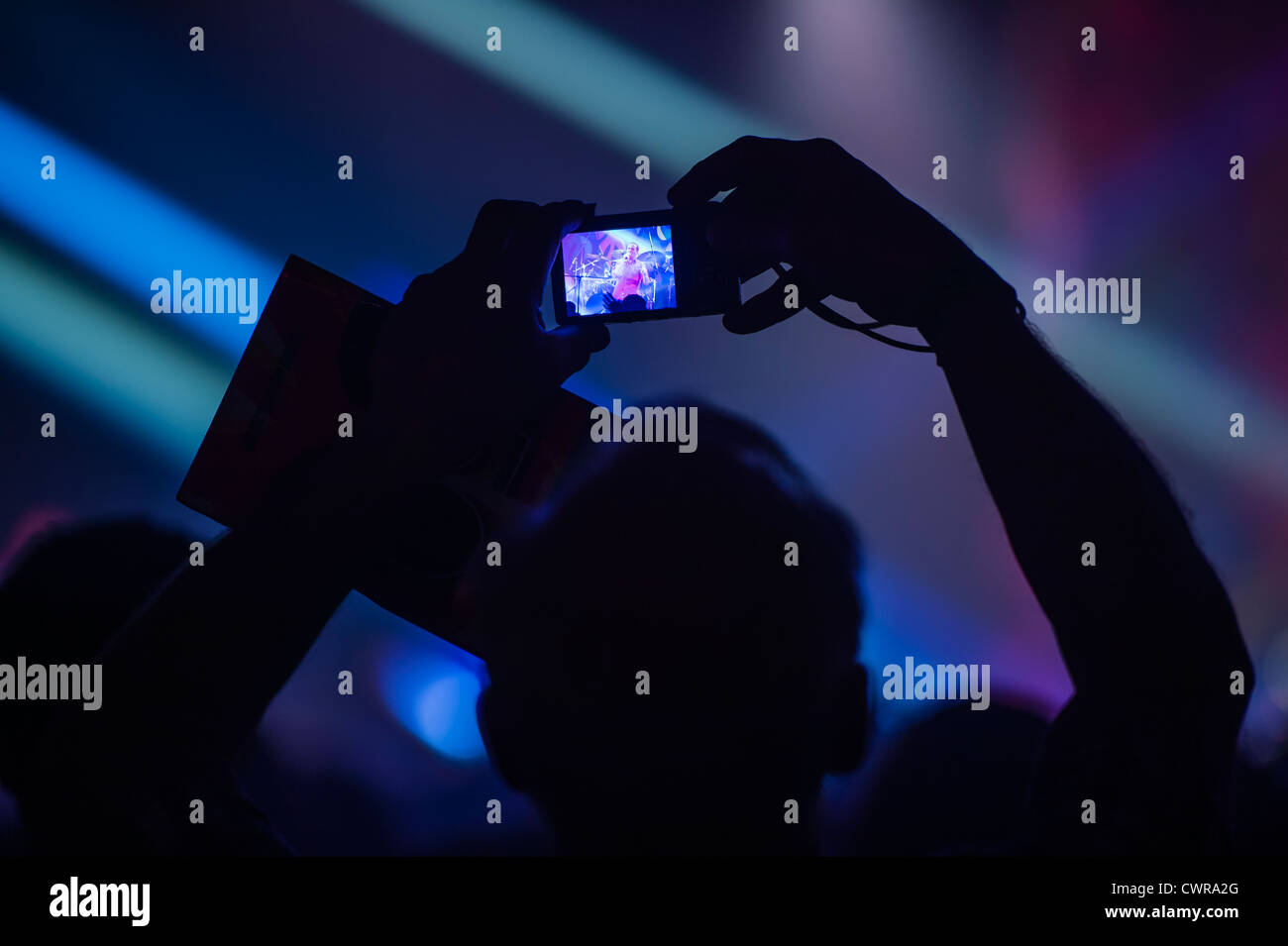 A person holding a mobile phone recording a band playing at concert gig ...