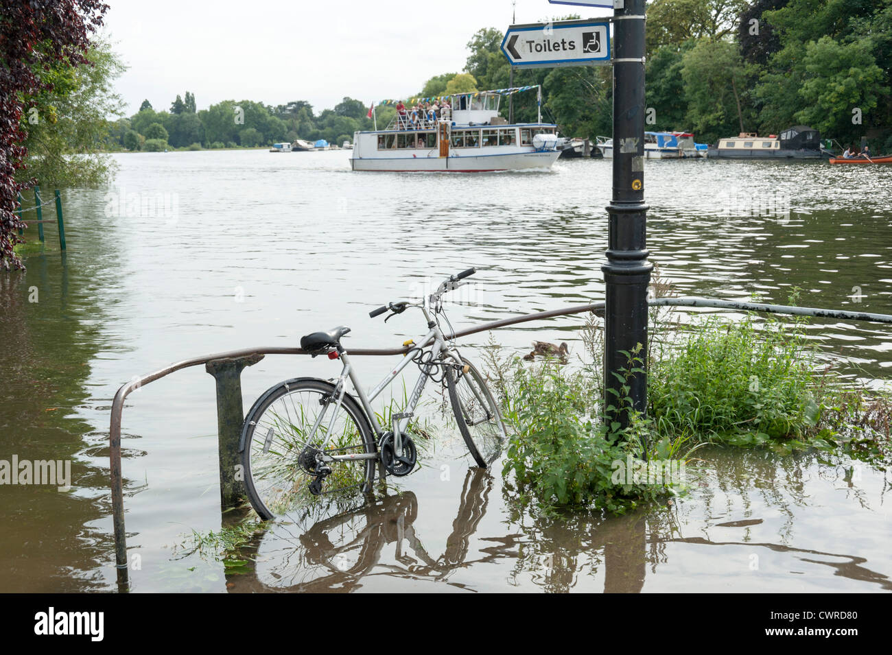 A cycle tied to railings flooded by high tide on the river Thames at ...