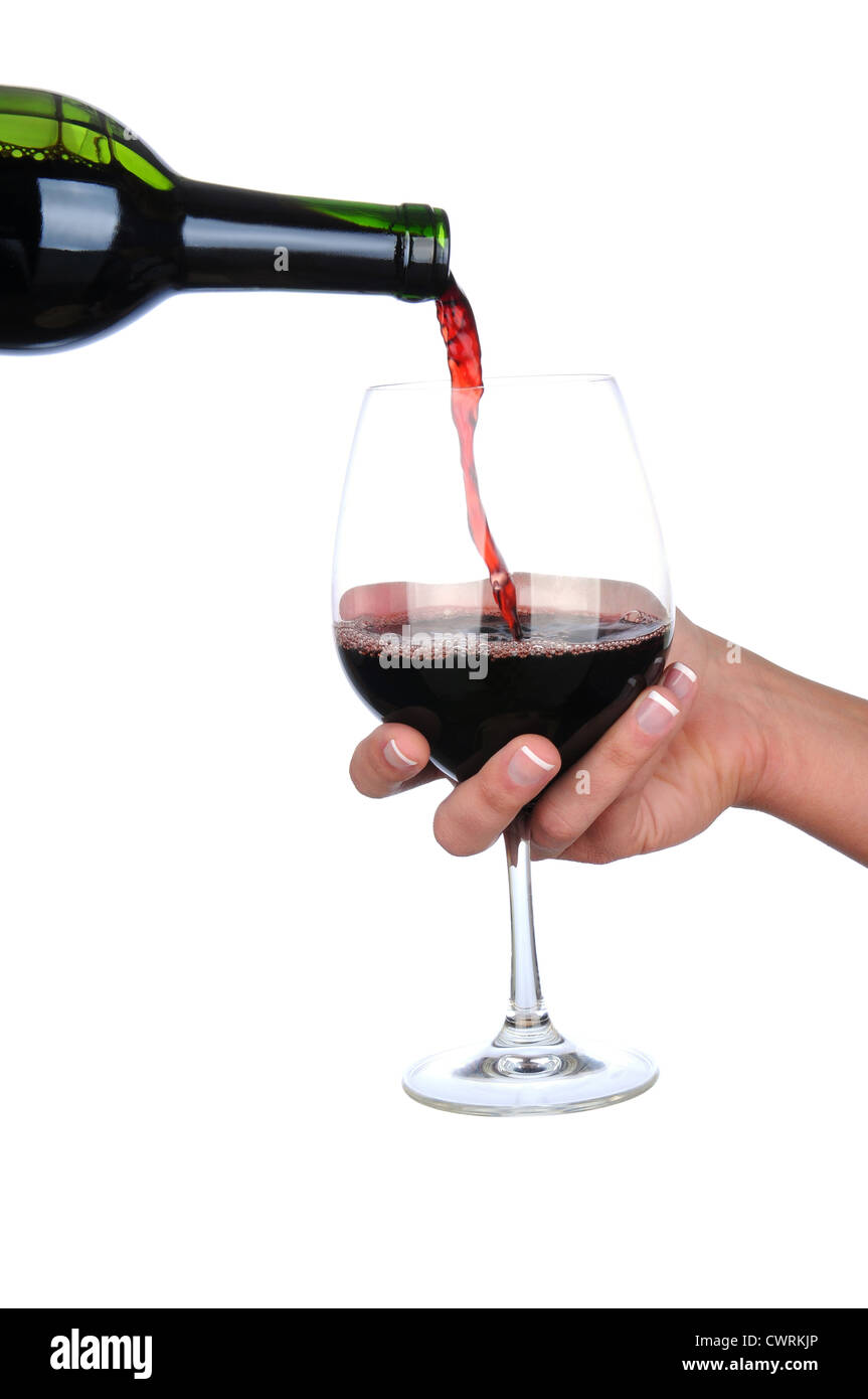 Closeup of red wine being poured from a bottle into a wineglass held in ...