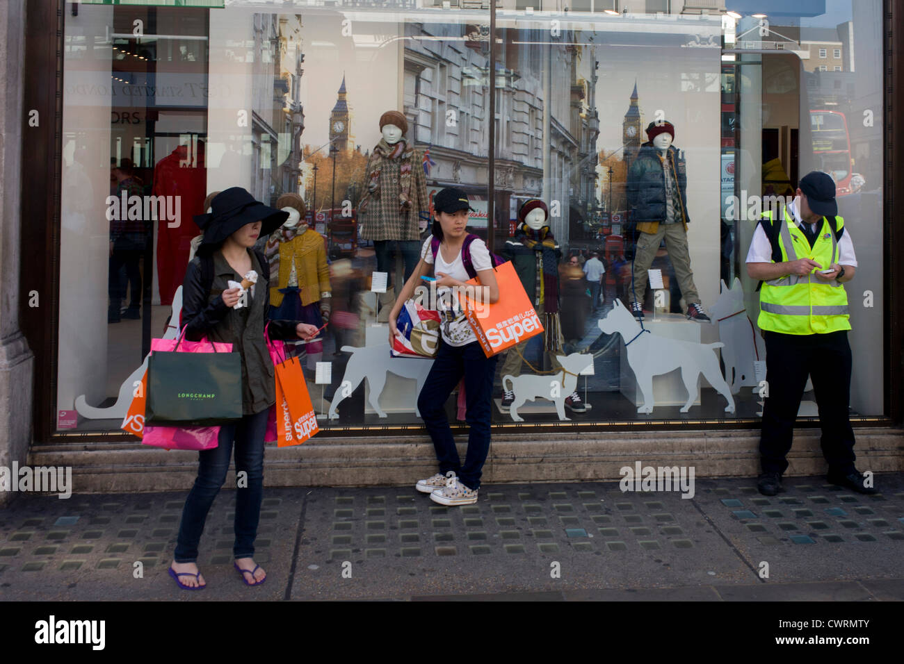 Spending foreign shoppers stand outside an Oxford Street shop window ...