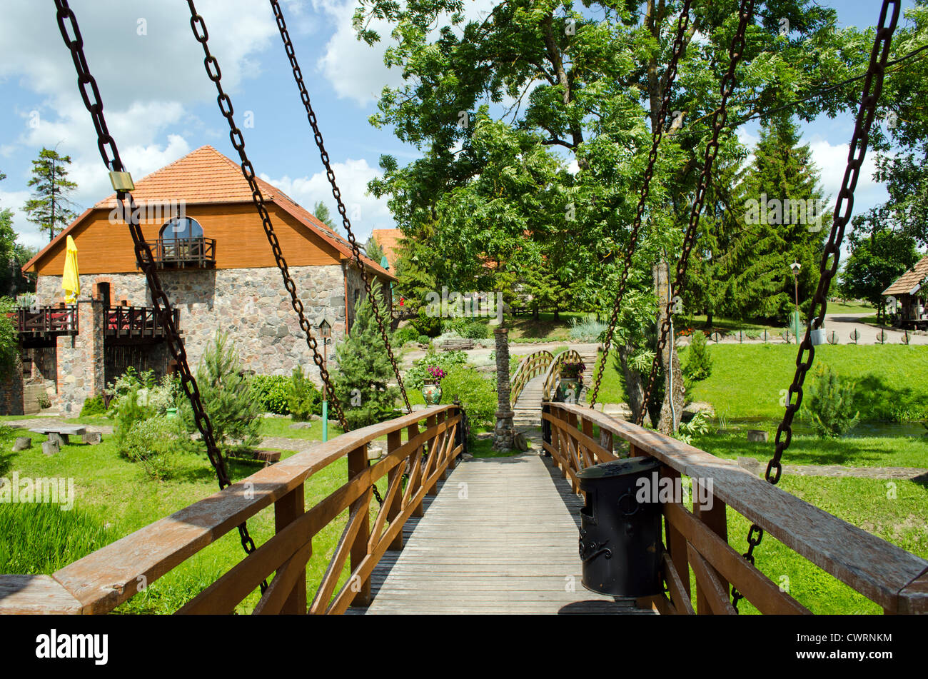 Rusty chains holding bridge in park and building wall made of stones ...