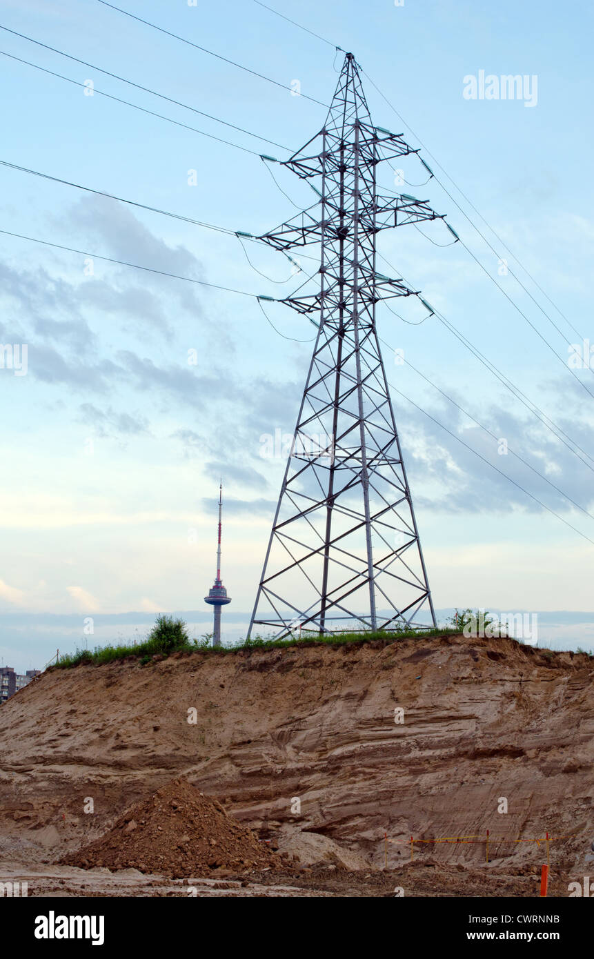 High-voltage power poles and wires on sand hill and television tower in ...
