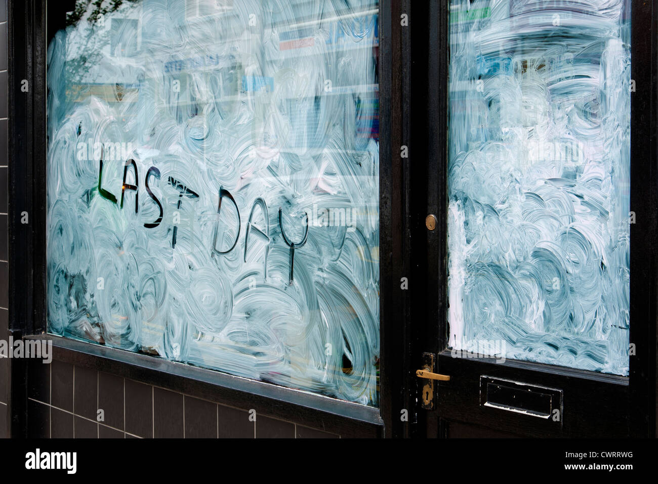 Shop front with white washed windows and the word 'LAST DAY' written on ...