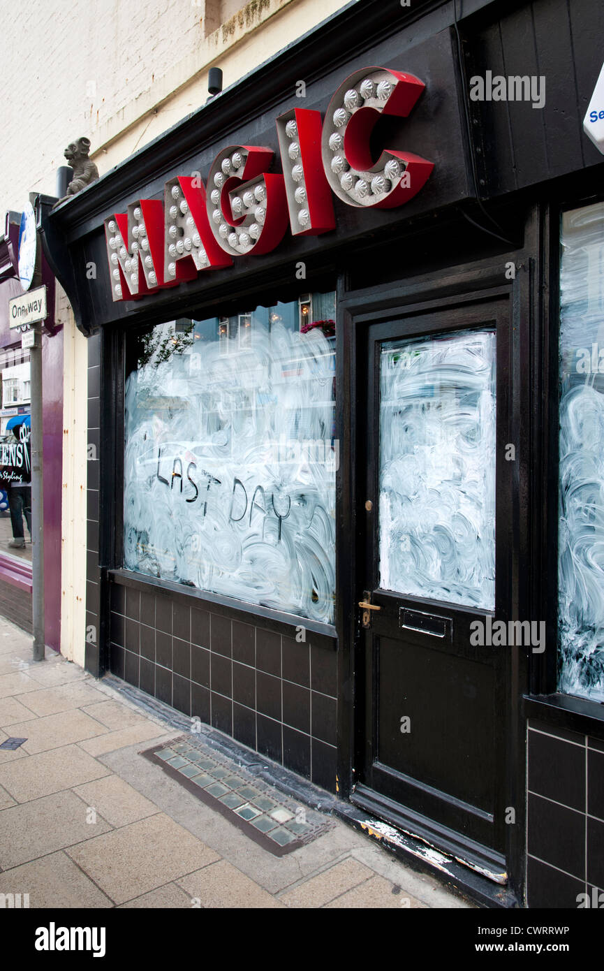 Magic store shop front with white washed windows and the word 'LAST DAY ...