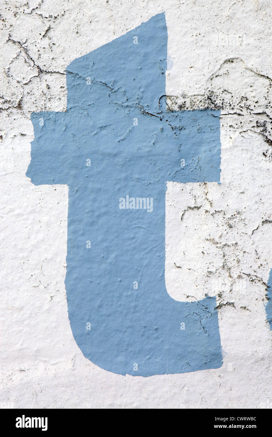 Lower case letter "t" in sky blue paint stenciled onto crumbling ...