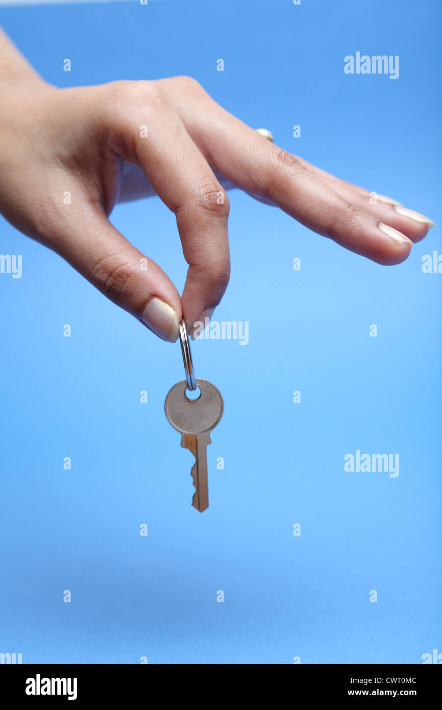 Hand holding a key isolated on blue background Stock Photo - Alamy