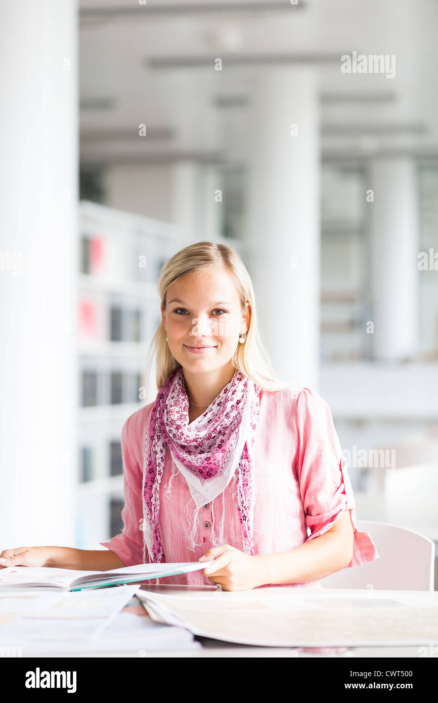 in the library - pretty female student with books working in a high ...