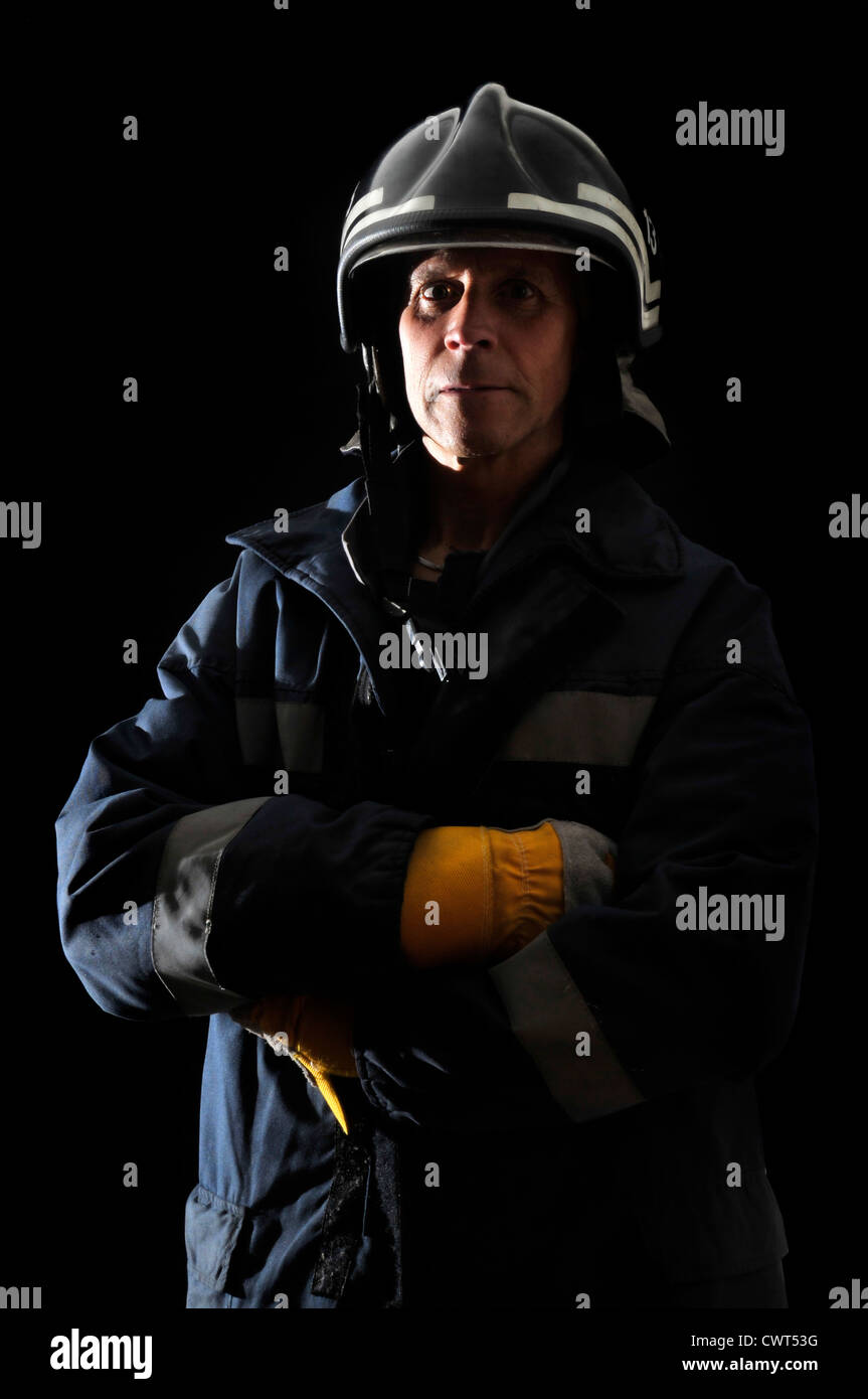 Fireman in uniform isolated in black Stock Photo - Alamy