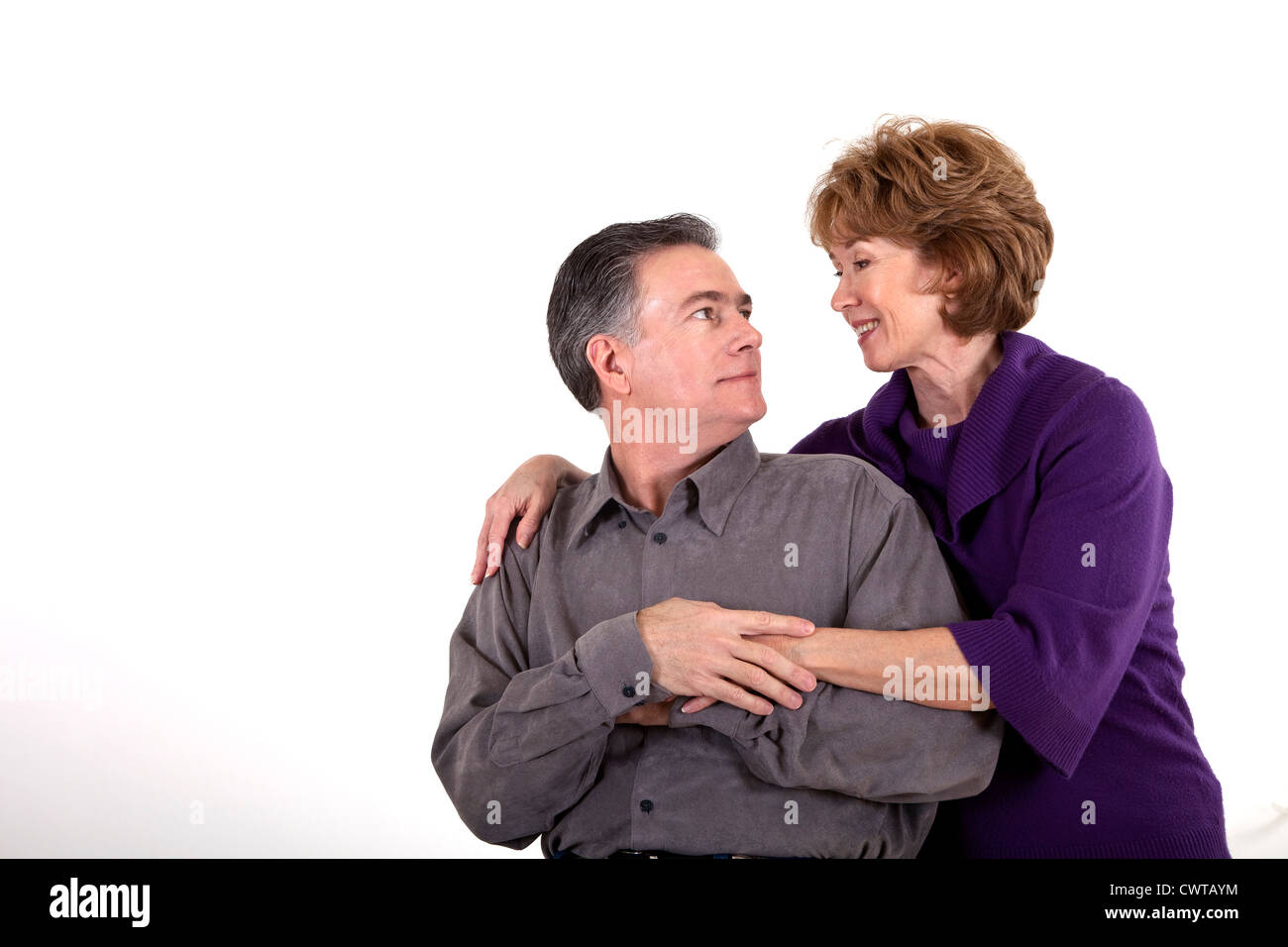 A mature couple affectionately hold each other and smile lovingly at ...