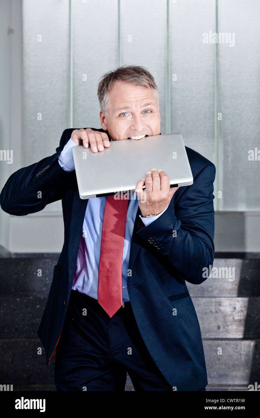 Businessman biting into laptop Stock Photo - Alamy