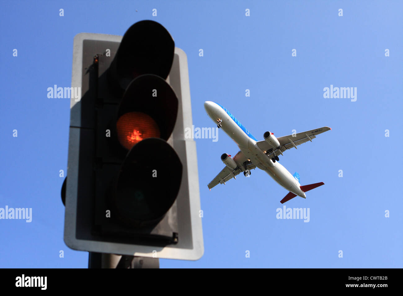 traffic lights against a blue sky with an aircraft coming to land at ...