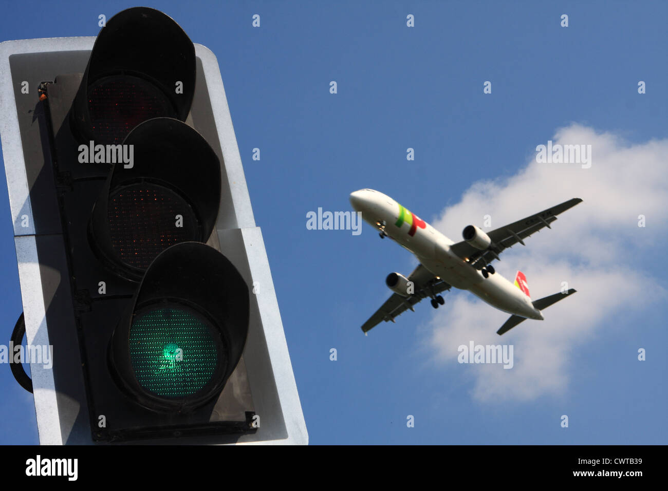 traffic lights against a blue sky with an aircraft coming to land at ...