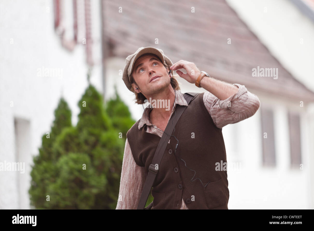 Man with earbuds and cap looking up Stock Photo - Alamy