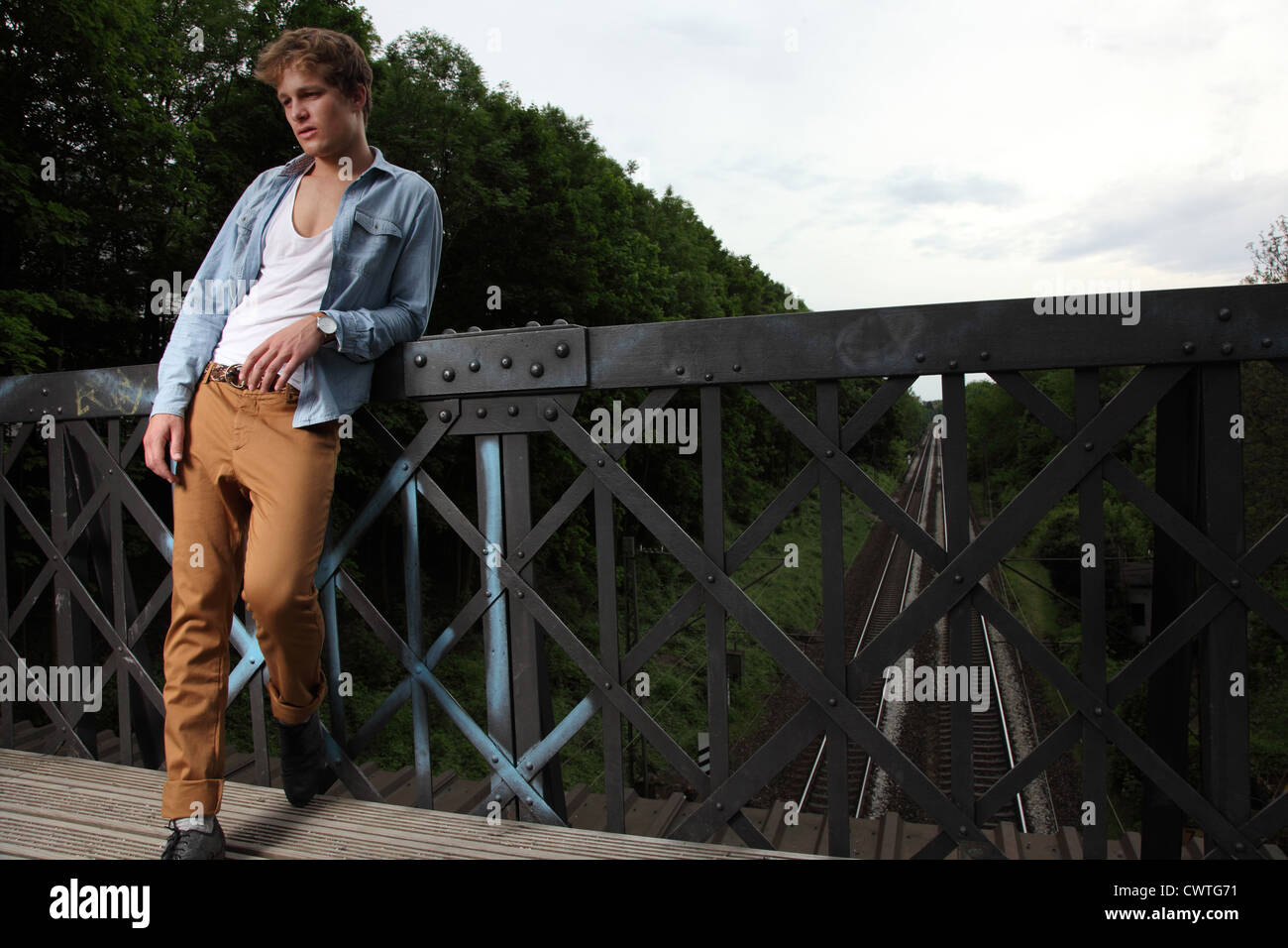 Serious young man standing on railroad bridge Stock Photo - Alamy