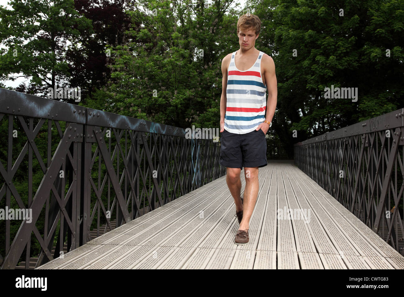 Serious young man crossing a bridge Stock Photo - Alamy