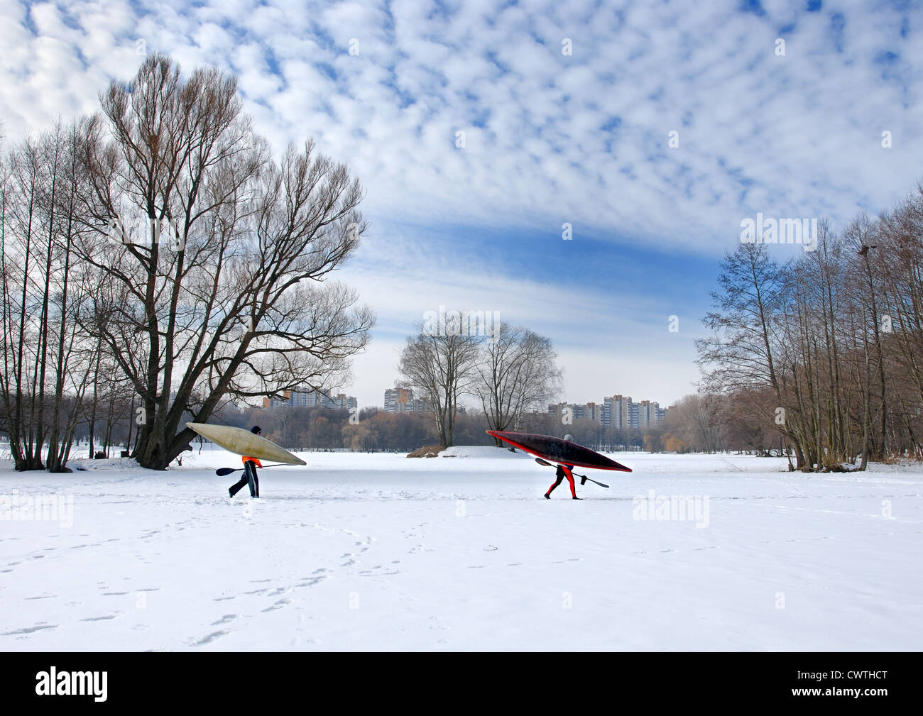 Two oarsmen with oars and kayaks go on ice of the frozen lake Stock ...