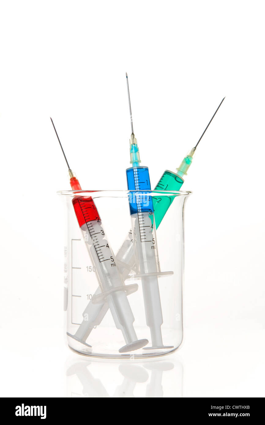 Three syringes with liquid in a beaker Stock Photo - Alamy