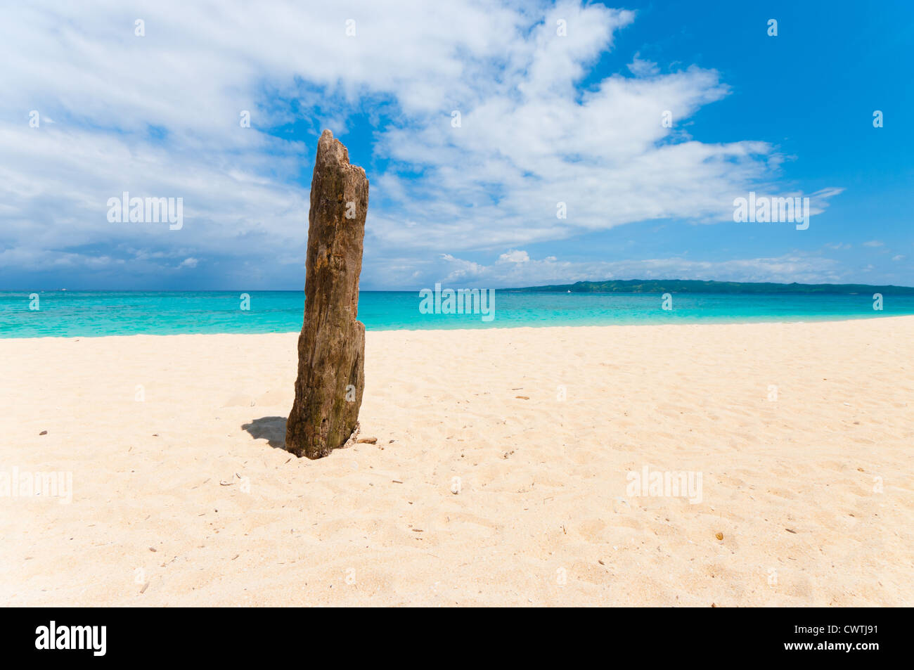 tropical beach with a wooden pole in the sand Stock Photo - Alamy