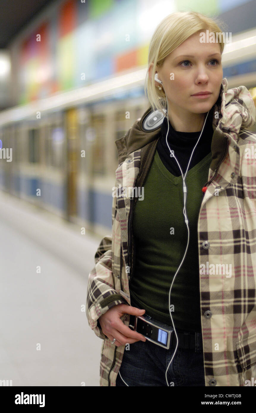 Young woman with earbuds in subway station Stock Photo - Alamy