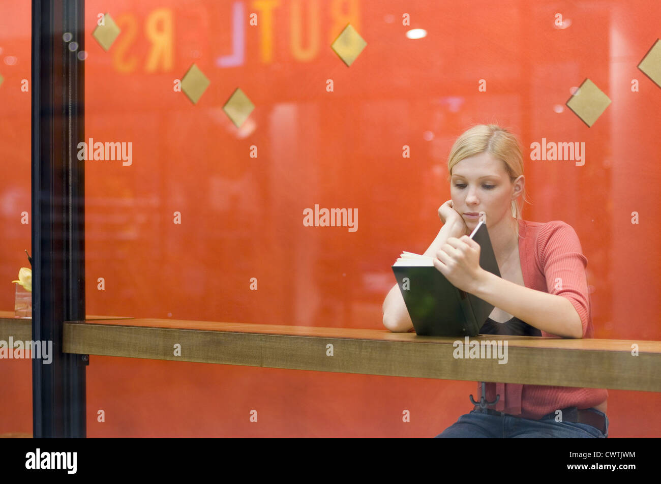Young woman reading book behind windowpane Stock Photo - Alamy