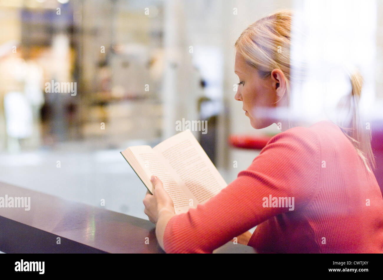 Young woman reading book behind windowpane Stock Photo - Alamy
