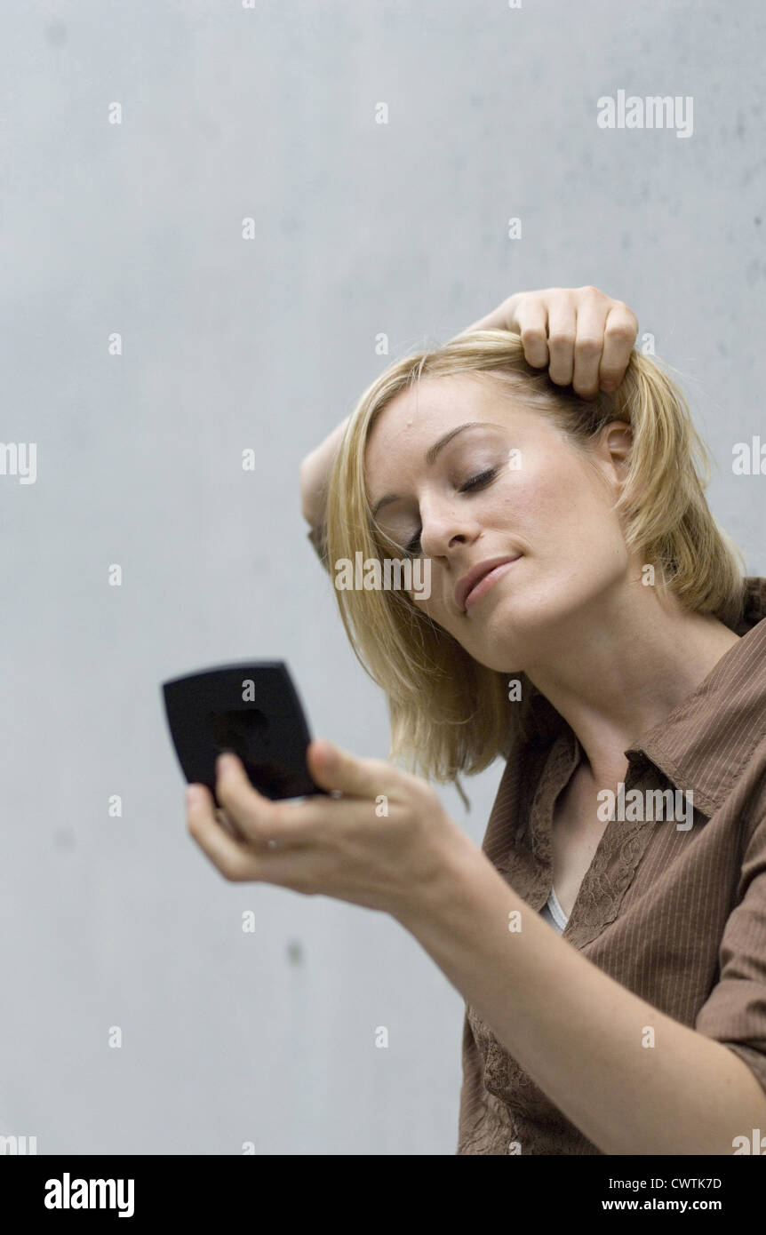 Young woman looking in hand mirror Stock Photo - Alamy