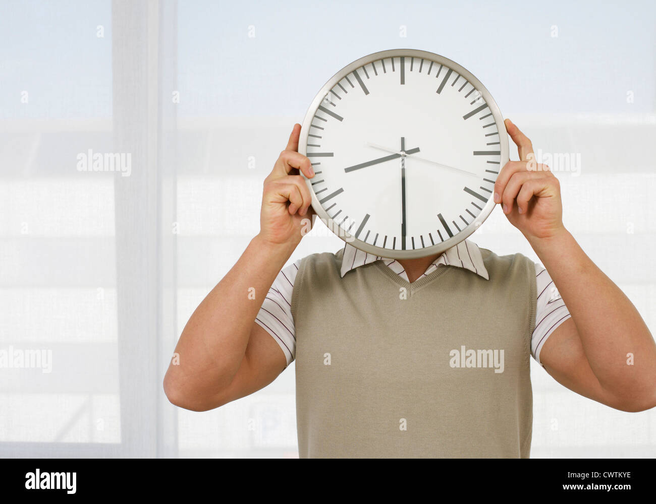 Man holding clock in front of his face Stock Photo - Alamy