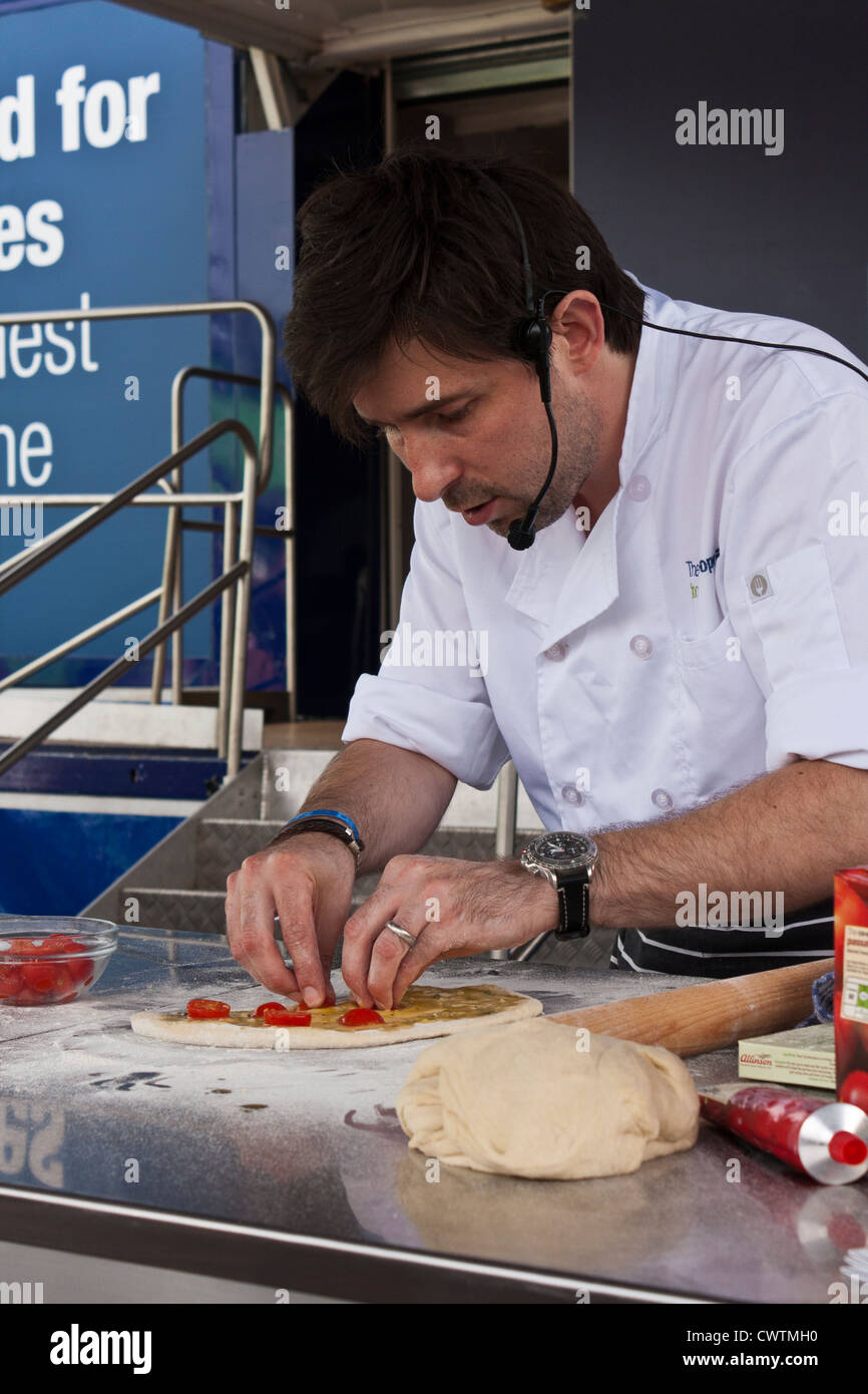 A chef from Co-operative Food adds toppings to a pizza base while ...
